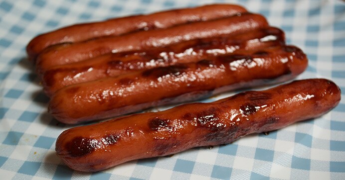 Grilled hotdogs on a blue and white checkered plate.