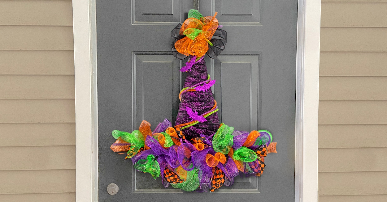 A witch’s hat wreath made out of purple, black, orange and green ...
