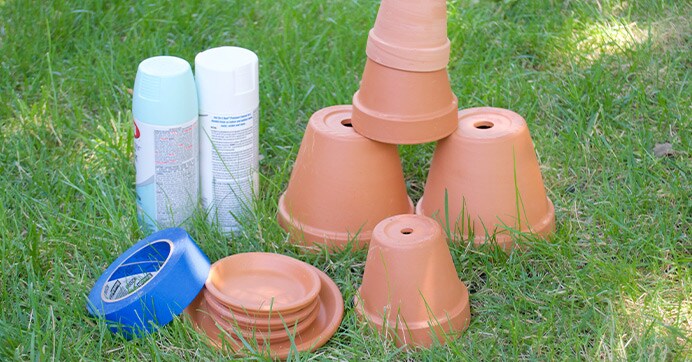 Cans of spray paint, terra cotta pots and lids, and a roll of painters ...