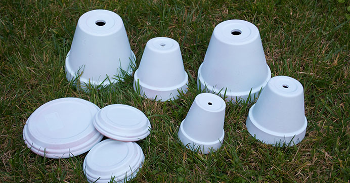 Terra cotta pots and lids that are painted white.