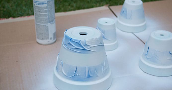 A can of spray paint and terra cotta pots with painters tape on it that ...