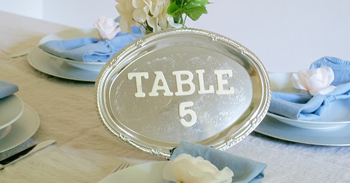 A silver serving tray with Table 5 on it and table settings with blue ...