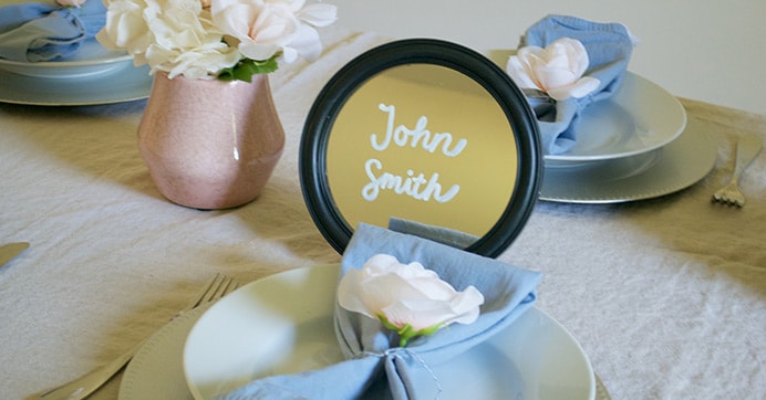 Table settings with blue cloth napkin and a pink vase with white ...