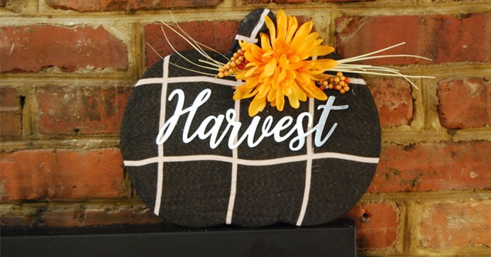 A black pumpkin sign with Harvest lettering and flowers on it, hanging ...