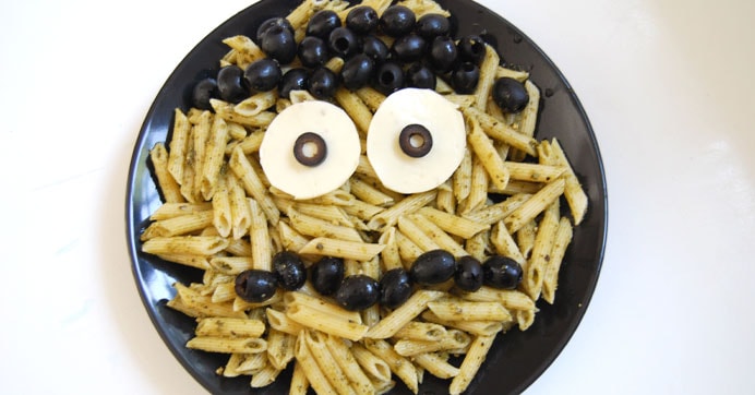 A plate with noodles and olives and cheese made to look like a face.