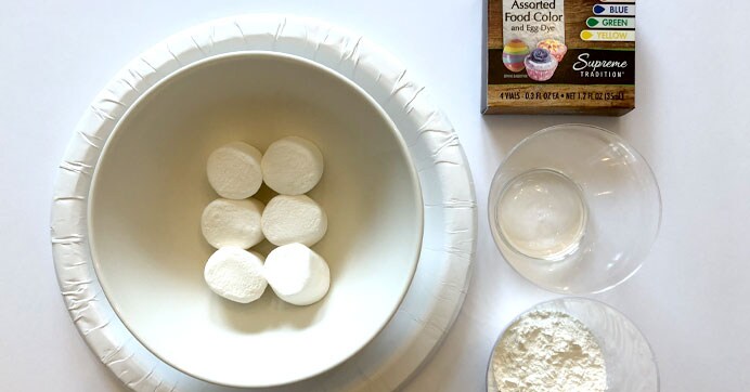 A bowl with marshmallows in it, a box of food coloring and two clear ...