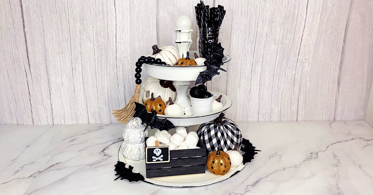 Rustic white tiered tray decorated with a variety of Halloween-themed ...
