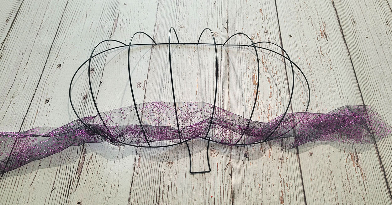 wire wreath form with hand holding decorative mesh that has been weaved ...