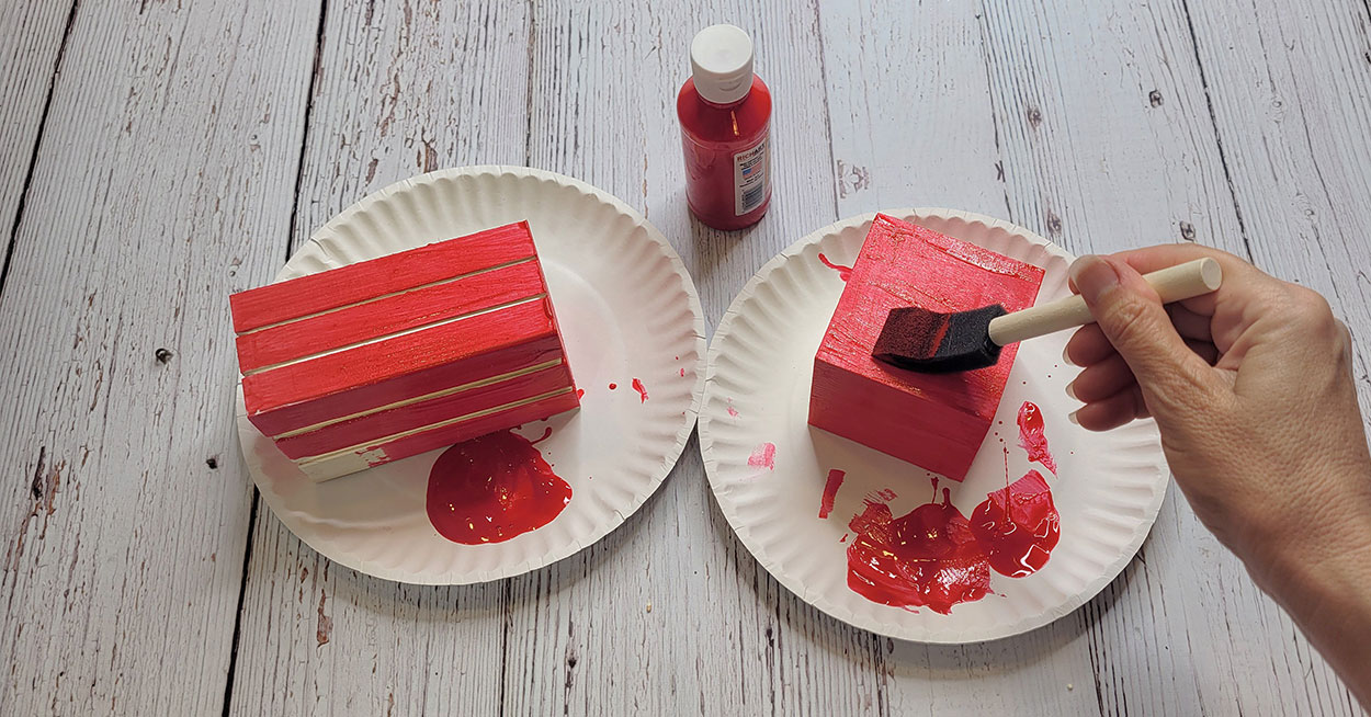 paper plates with wooden crates and box being painted by a hand with ...