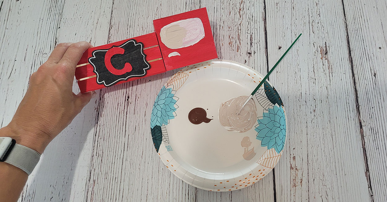 hand holding red truck with a plate with paint on it