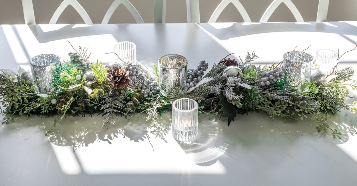 Holiday centerpiece with candleholders and frosted greenery, silver ...