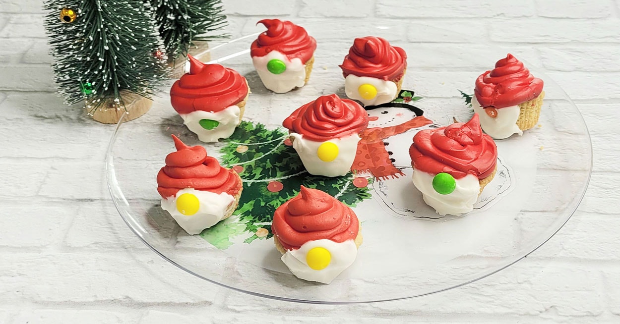 A Christmas-themed plate filled with mini cupcakes decorated with red ...