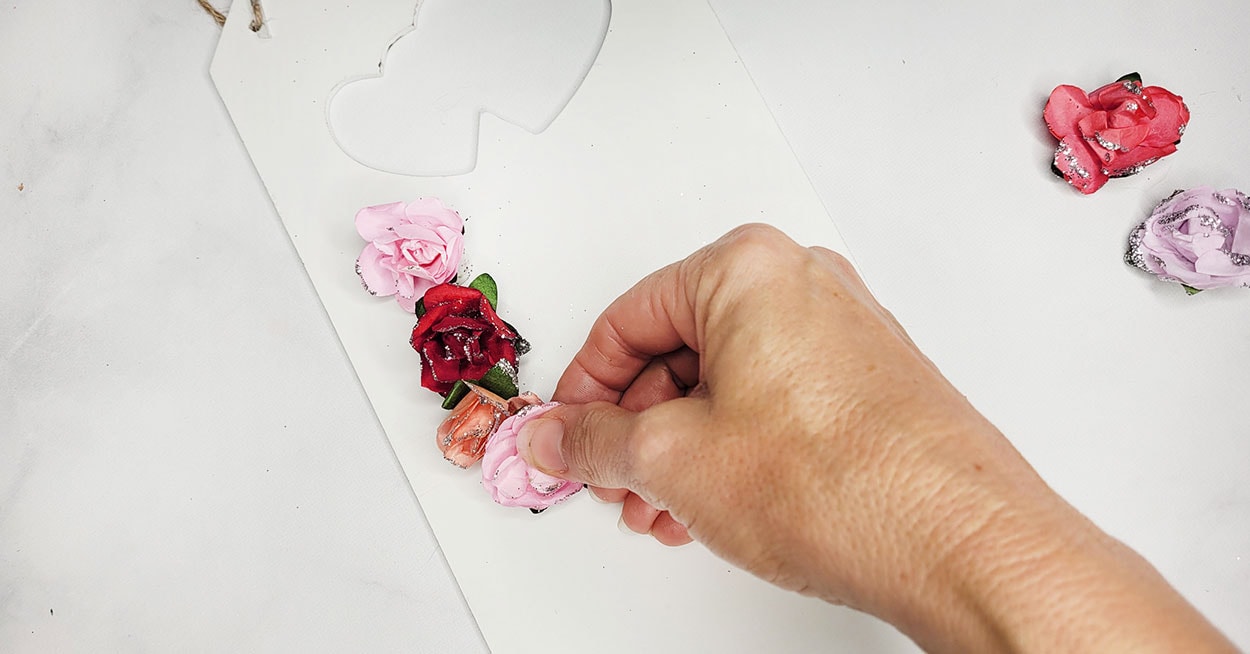 A hand putting paper hearts on a white hanging sign.