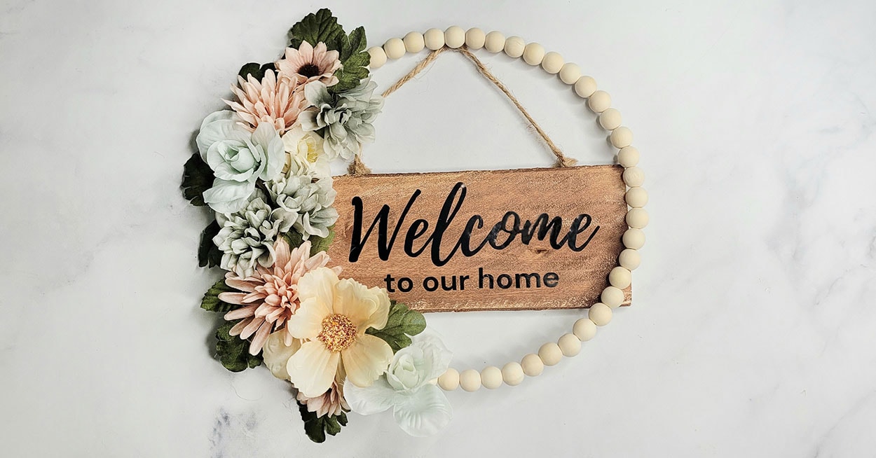 A round beaded wreath decorated with muted pastel farmhouse floral and ...