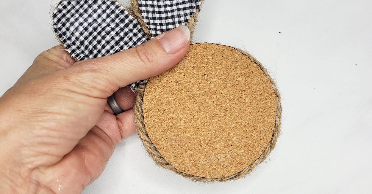 A hand holding a bunny coaster that has adhesive cork on the back.
