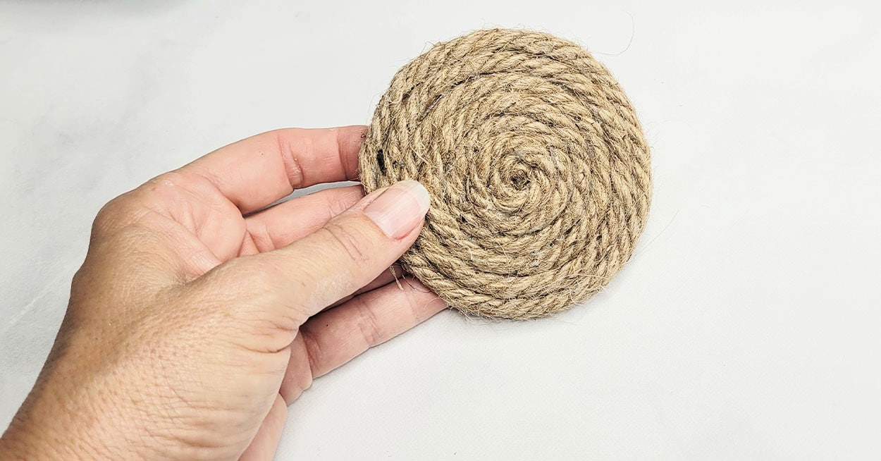 Hand holding a round coaster made from nautical rope.