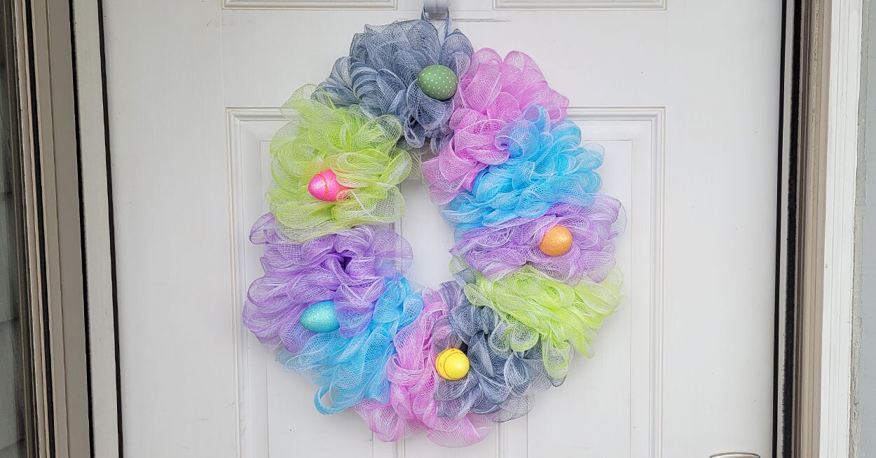 An egg-shaped Easter wreath decorated with pink, green, blue, purple ...