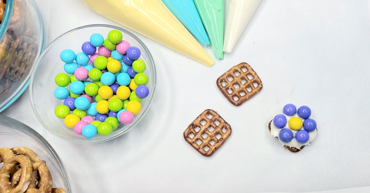 Bowls of pretzels and pastel candies with icing in piping bags