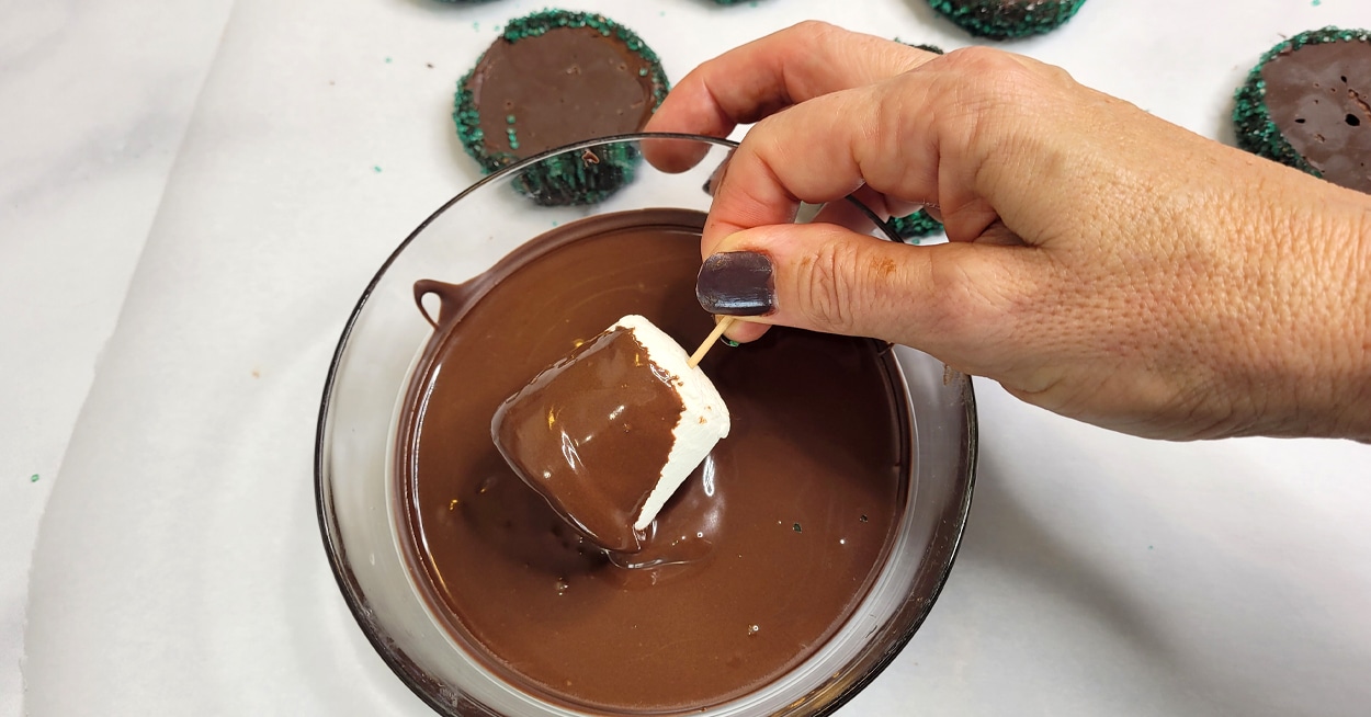 A hand holding a toothpick with a marshmallow on it that is being ...