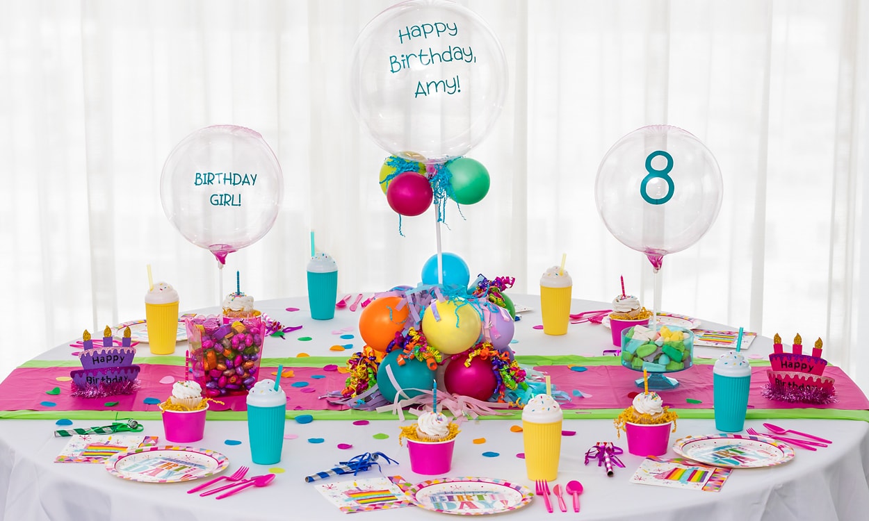 A birthday tablescape featuring 3 pink bubble balloons and colorful ...