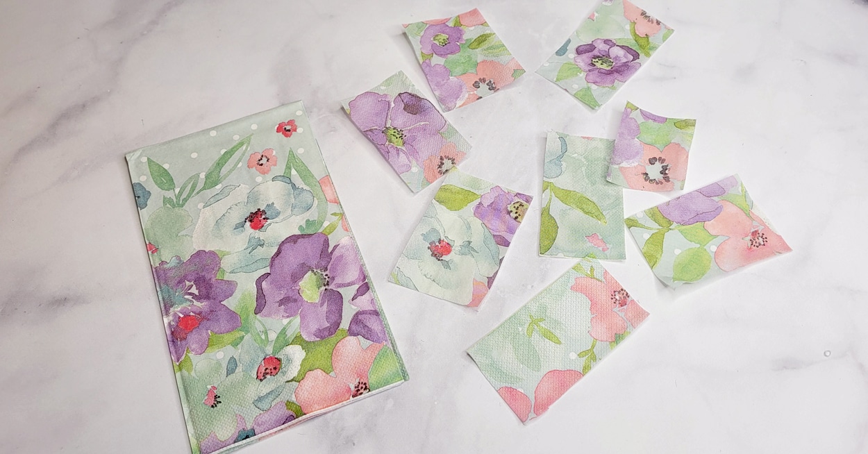 A flowered napkin and small squares of the napkin beside it.
