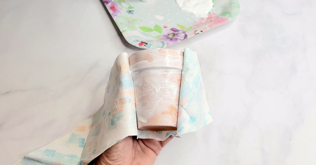 A hand holding a pot covered in glue and a strip of fabric, and a ...