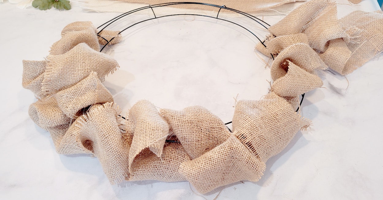 A wire wreath form burlap weaved through it.