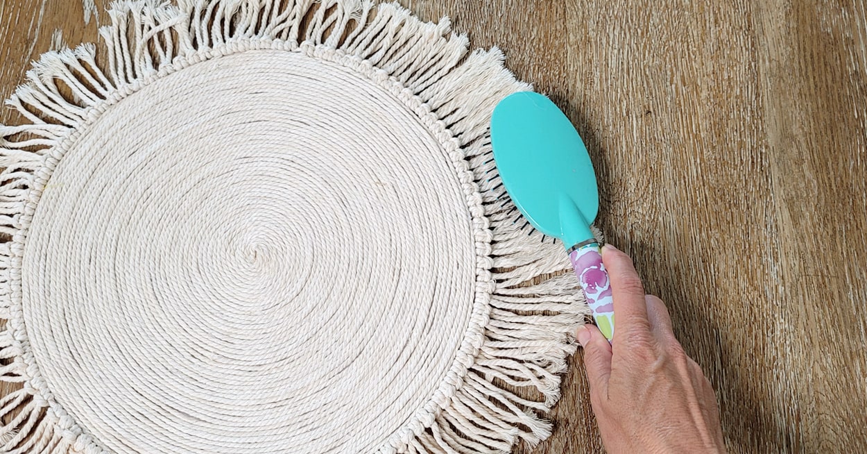 A round piece of foam board covered in macrame cotton twine with some ...