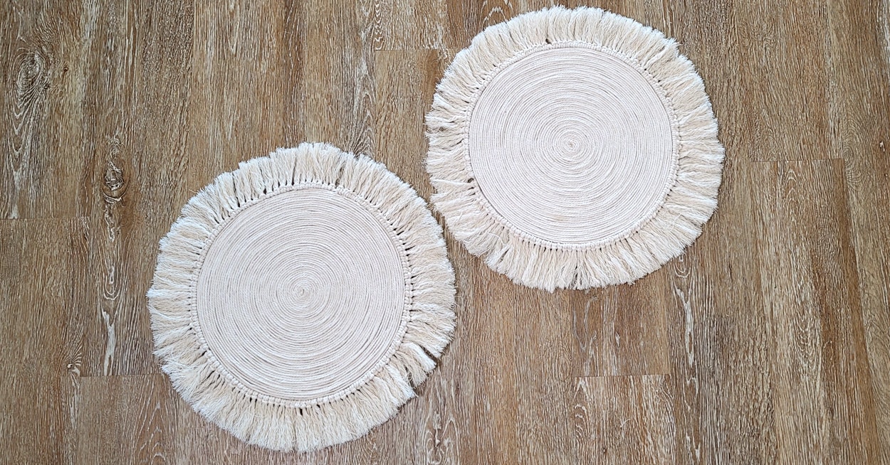 Two round placemats with fringe made from macrame cotton twine.