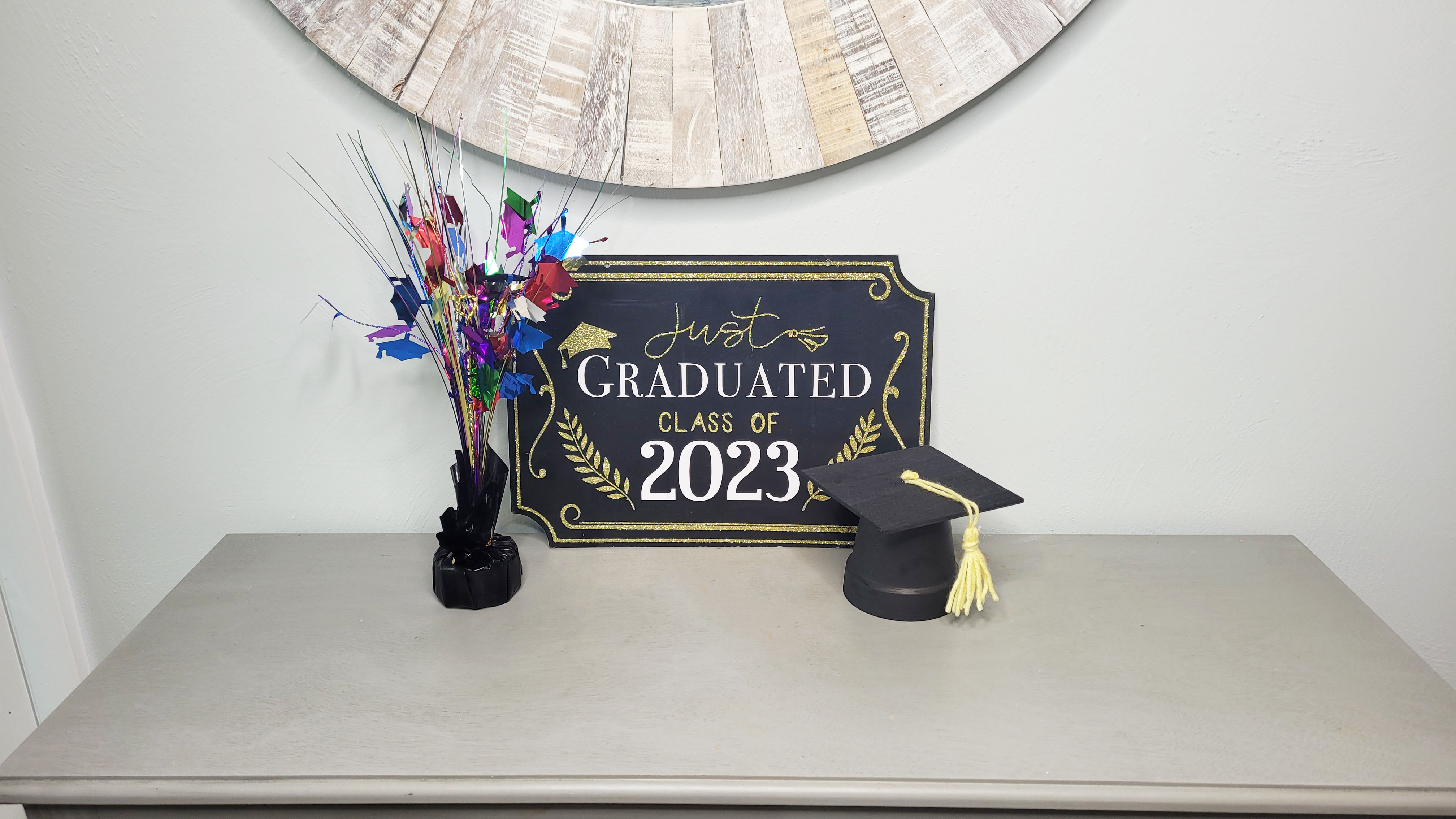 A balloon weight, a graduation sign and small graduation hat made from ...