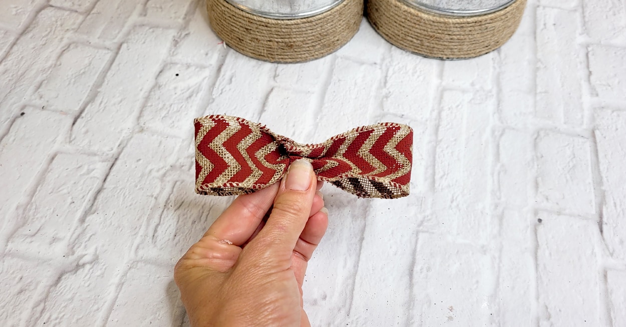 A hand holding ribbon in the shape of a bow.