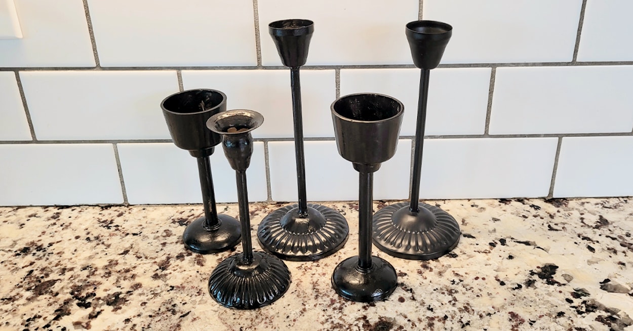 Five black candlesticks on a kitchen counter.