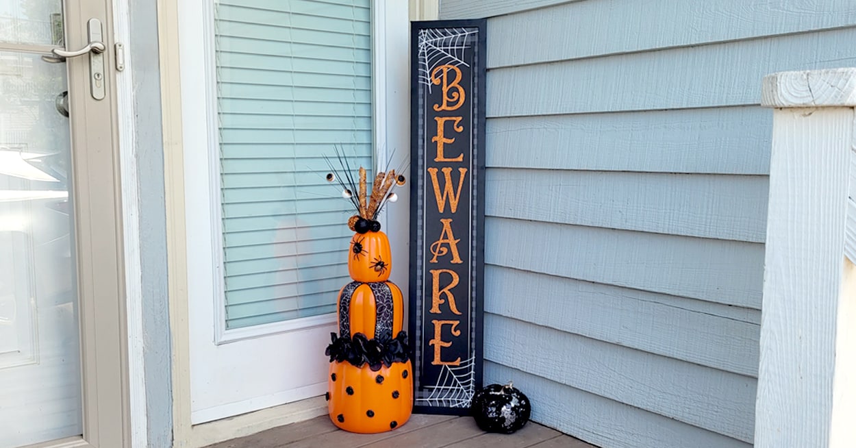 Three stacked plastic pumpkins next to a “Beware” leaning sign and a ...
