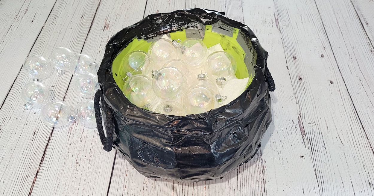 A bucket with paper towels and clear round balls in it and beside it.