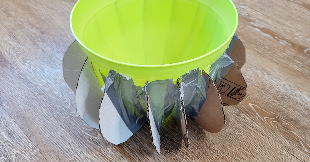 A green flowerpot with cardboard shapes glued on it and secured with ...