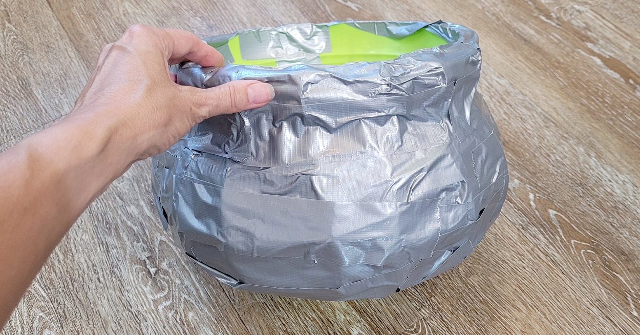 A hand holding a pot covered in duct tape.