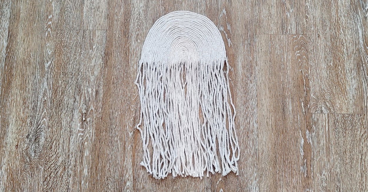 A semi-circle piece of foam board with pieces of yarn hanging on it.