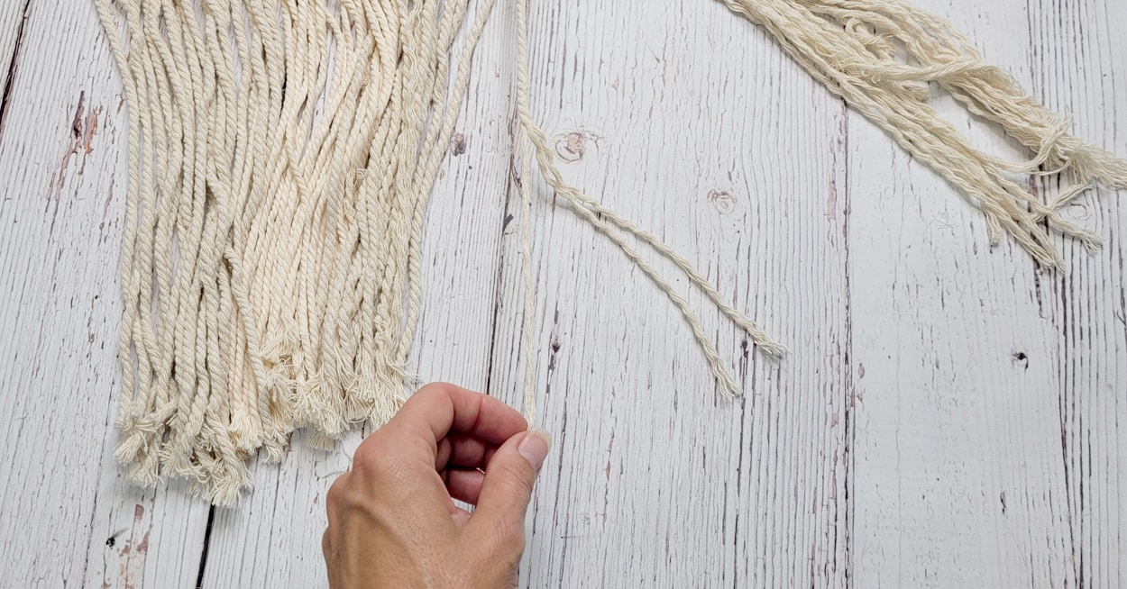 A hand holding pieces of macrame yarn.