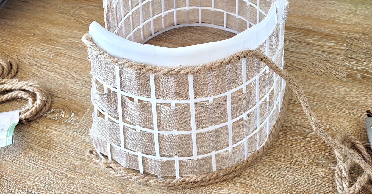 A laundry basket with burlap ribbon weaved through it and some ...