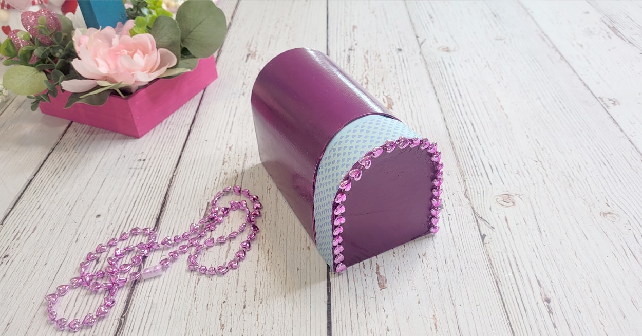 A small decorative mailbox and a purple heart necklace.