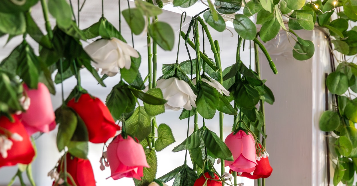 Alt. Text: Faux greenery and roses fashioned into a garland hanging on ...
