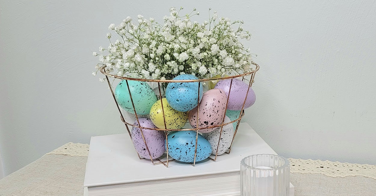 A DIY wire basket with Easter eggs and baby’s breath in it on a hall ...
