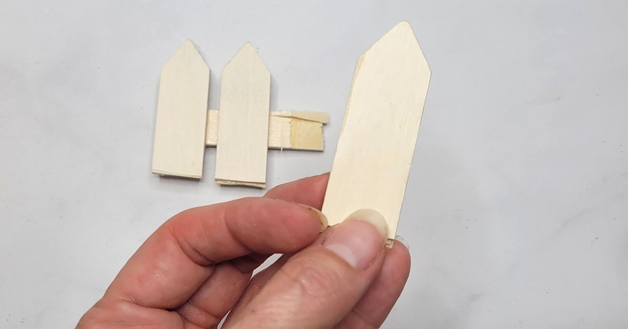 A hand holding a small pointy piece of wood.