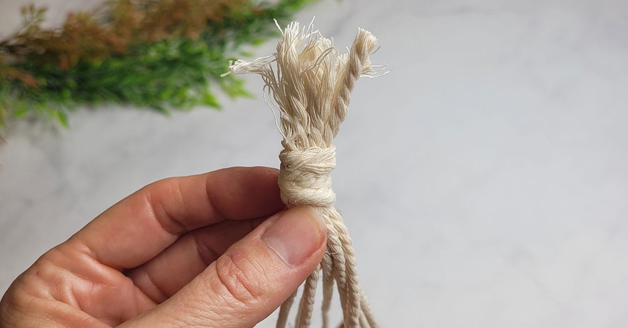 A hand holding pieces of rope gathered together.