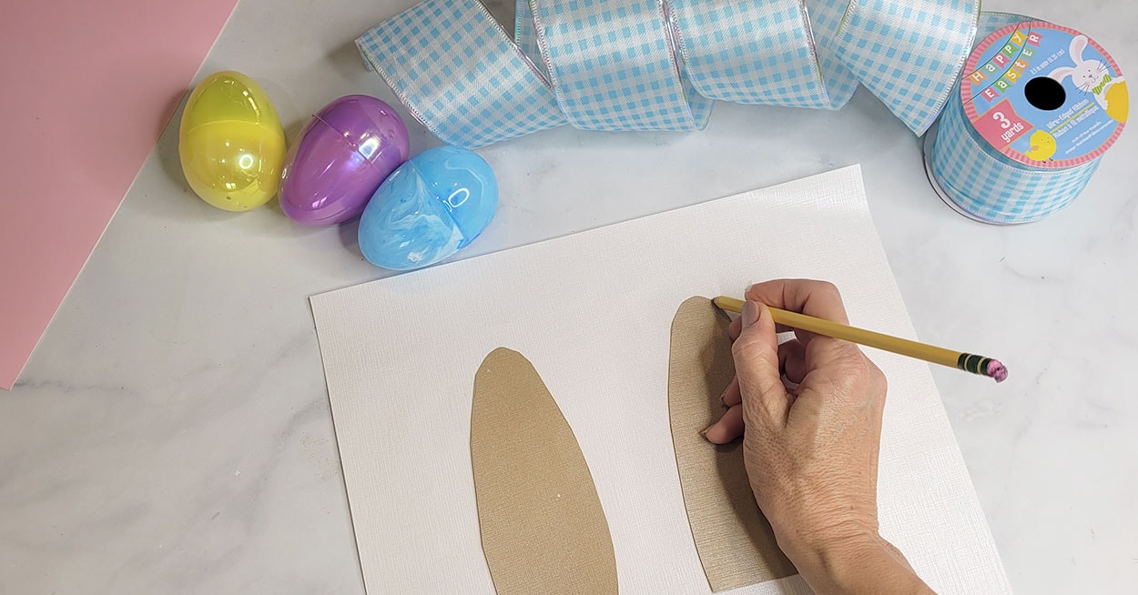 A hand tracing bunny ears on paper.