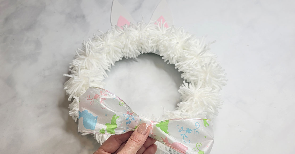 A pom pom bunny wreath on a wall.