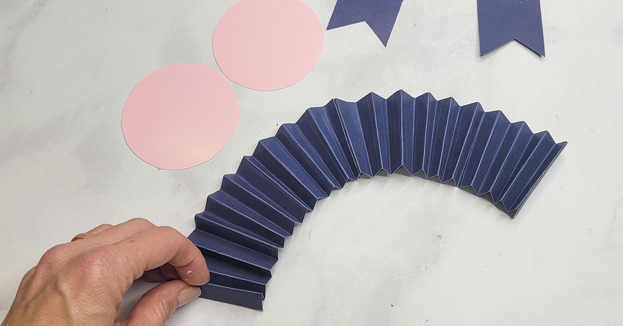 A hand holding a piece of paper folded like an accordion.