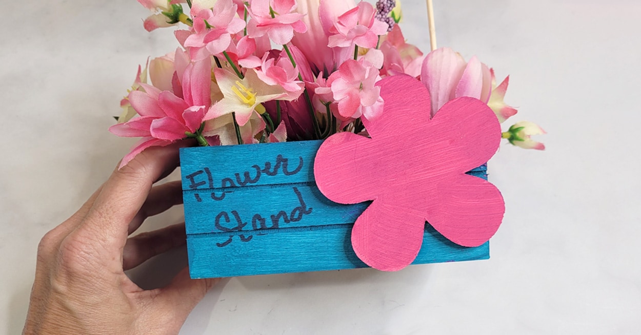 Hand holding a mini decorative pink and blue flower stand made out of ...
